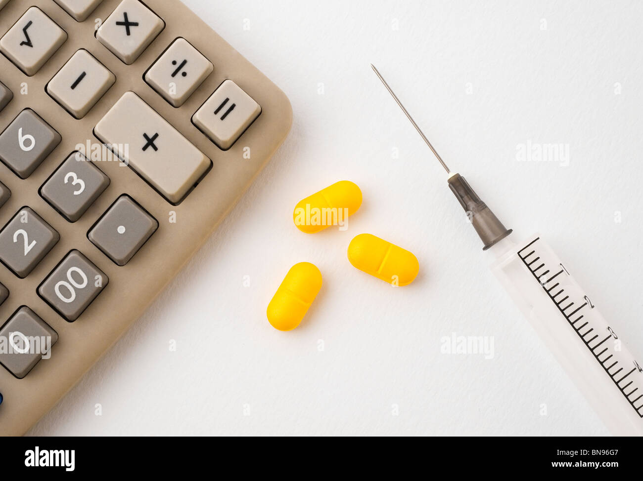 Electronic calculator with a medical syringe and pills on a white ...