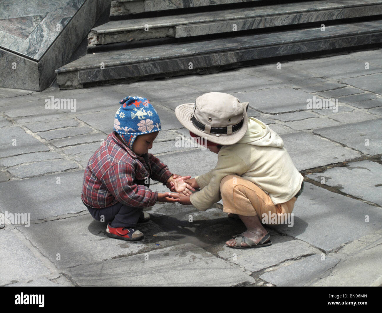 La Paz two small children wash their hands in a puddle Stock Photo - Alamy