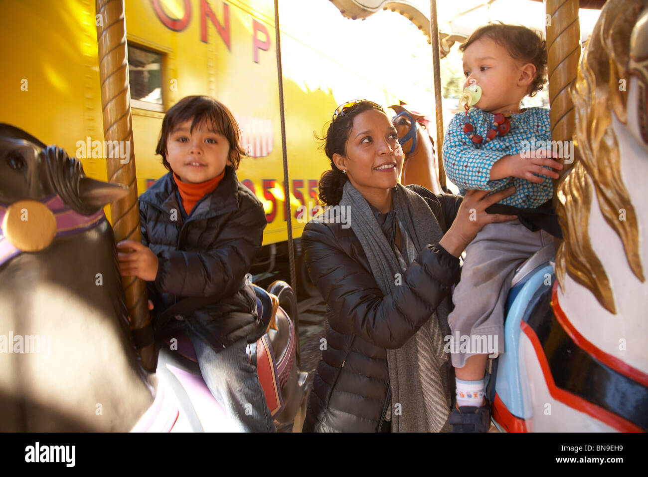 Mother and children enjoying carousel ride Stock Photo - Alamy