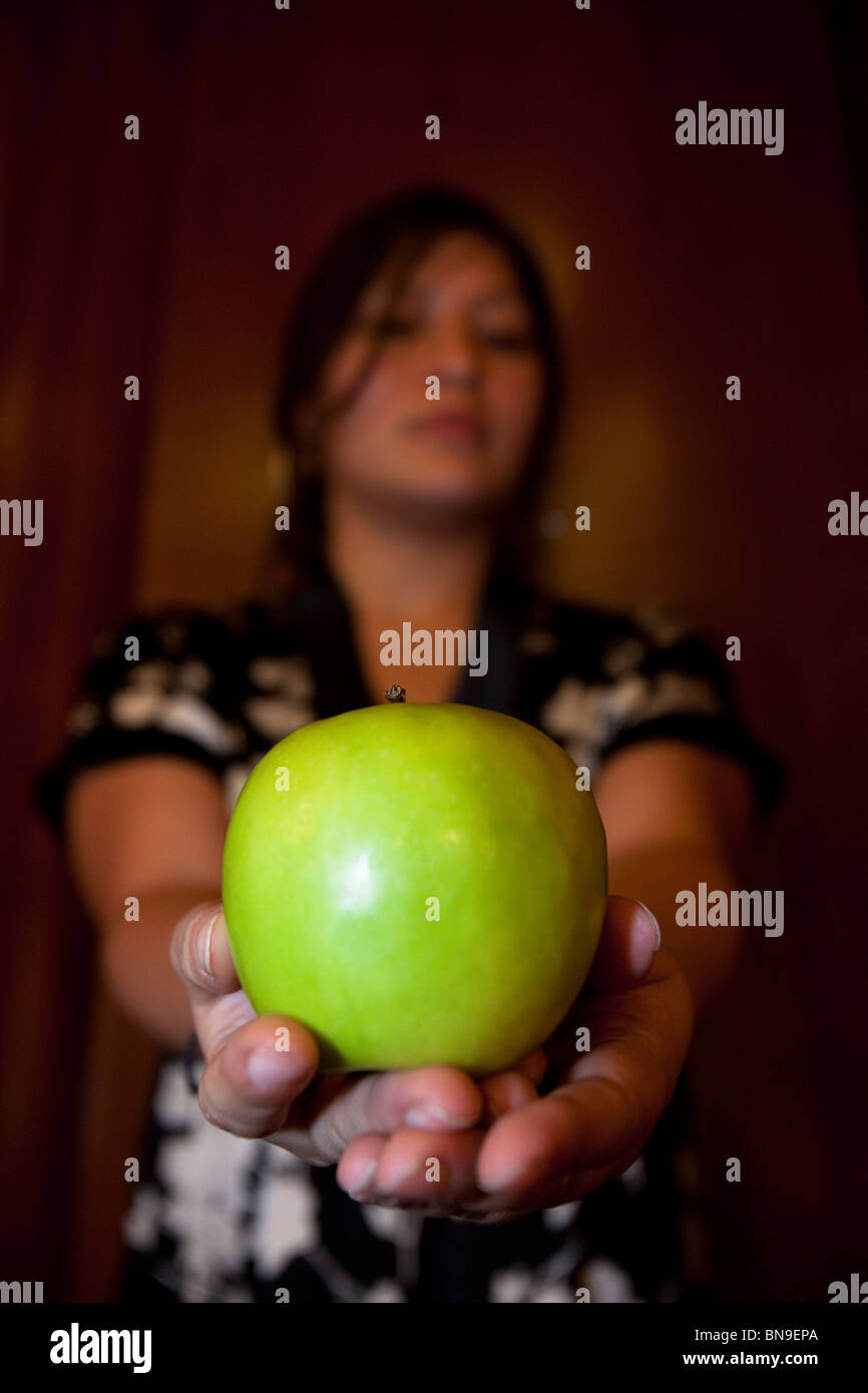 Female holding out a green apple in both hands Stock Photo - Alamy