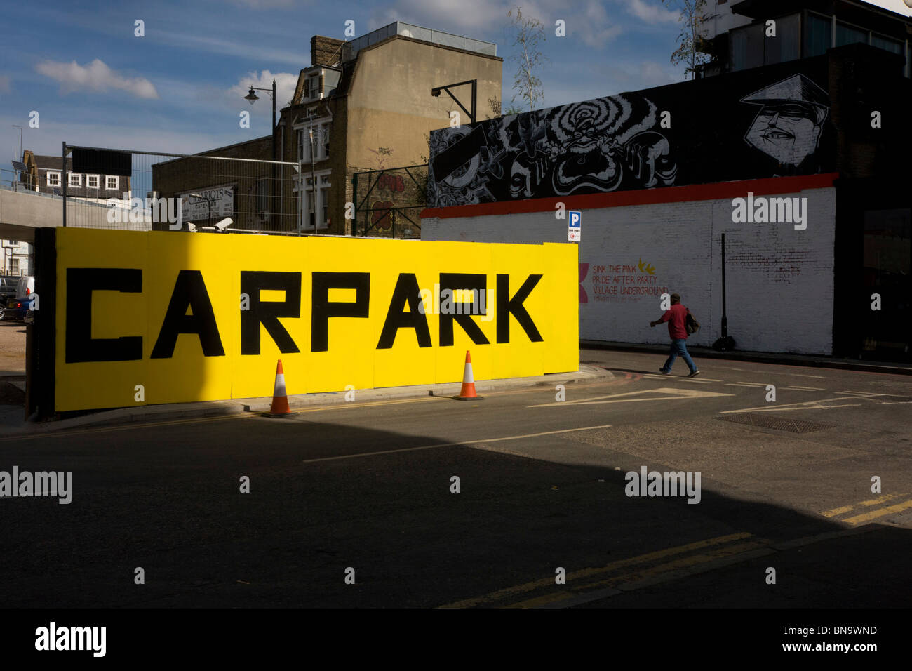 Man walks past a large yellow car park sign on street in East London ...