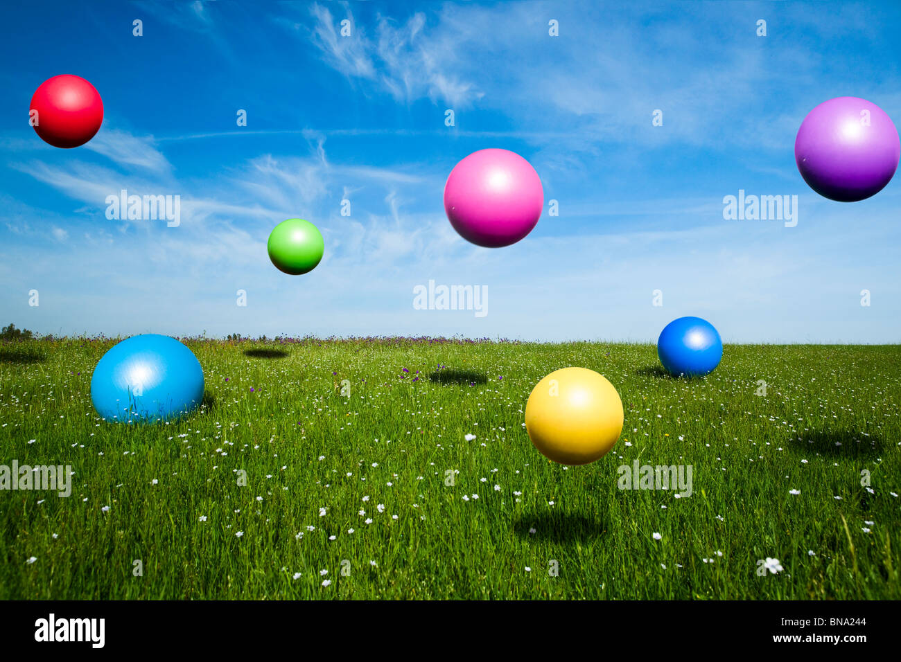 Colored balls jumping on a green meadow Stock Photo - Alamy