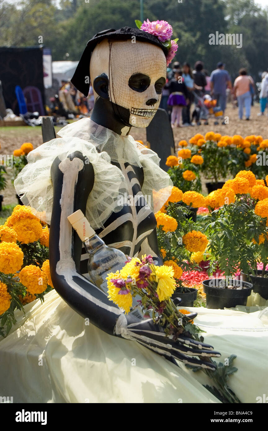 Catrina holding some cempasuchil flowers and a bottle of tequila in a ...