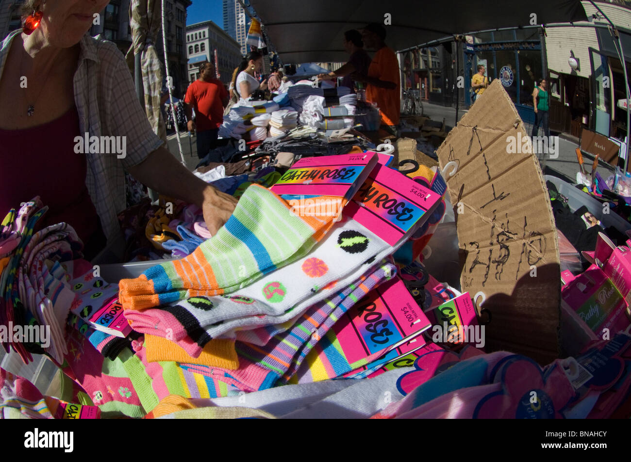 Shoppers browse socks and other goods at a vendor in a street fair on ...
