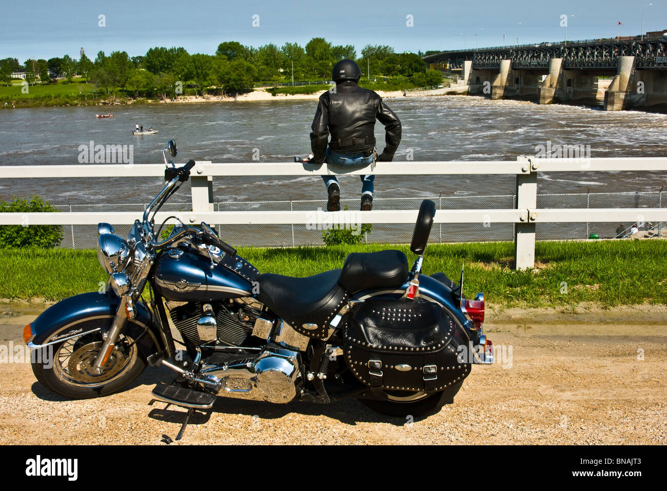 motorcyclist sits on fence looking at hydroelectric power dam Stock ...
