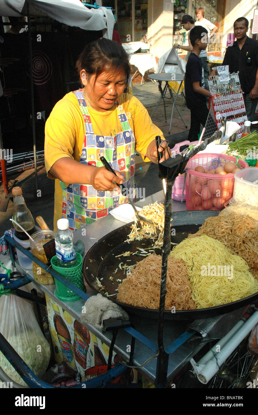 A cheerful food vendor tosses noodles in a Bangkok Street Thailand ...
