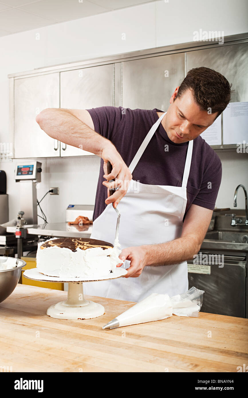 Male chef icing a cake in commercial kitchen Stock Photo - Alamy