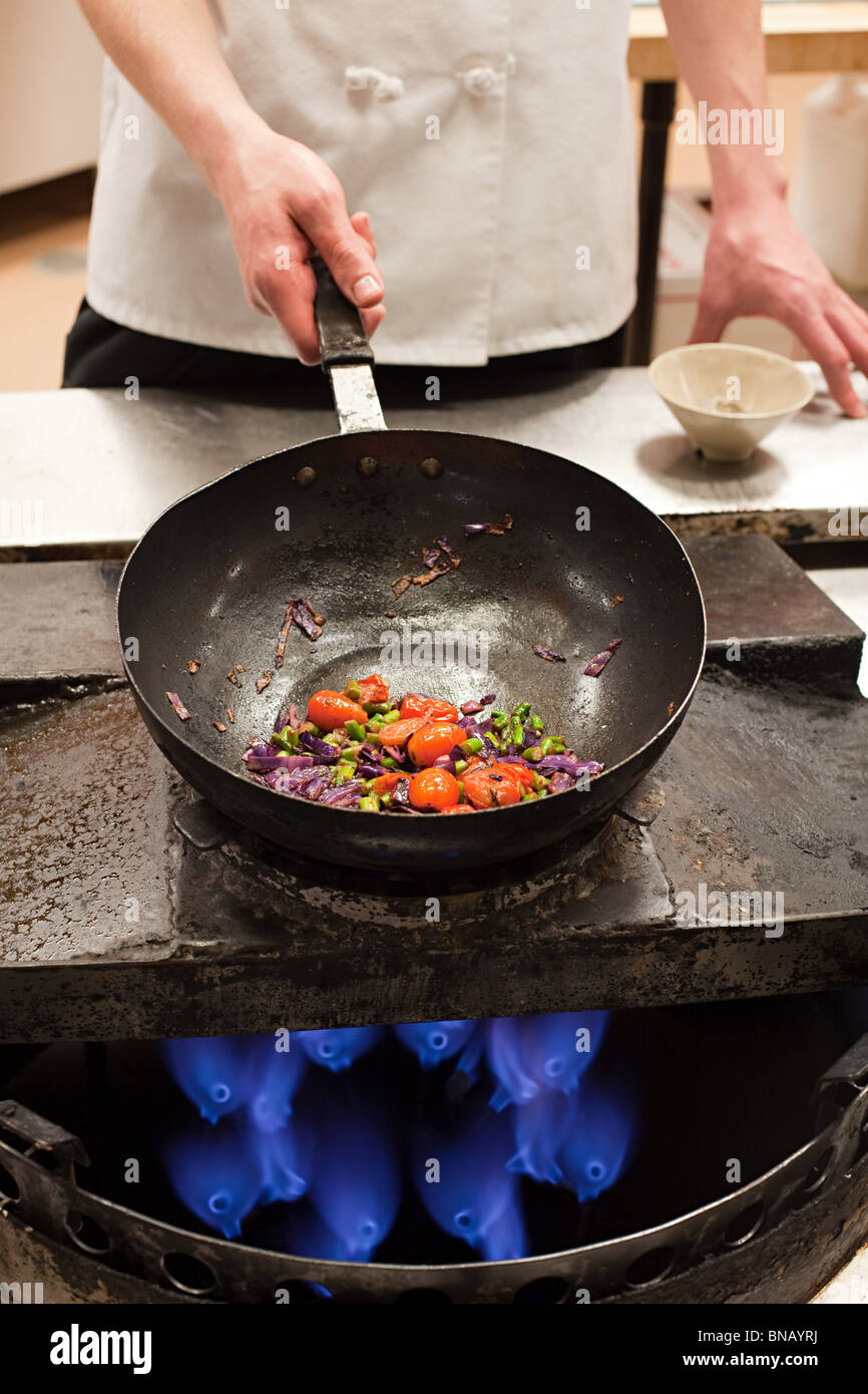 Male chef frying with wok in commercial kitchen Stock Photo - Alamy