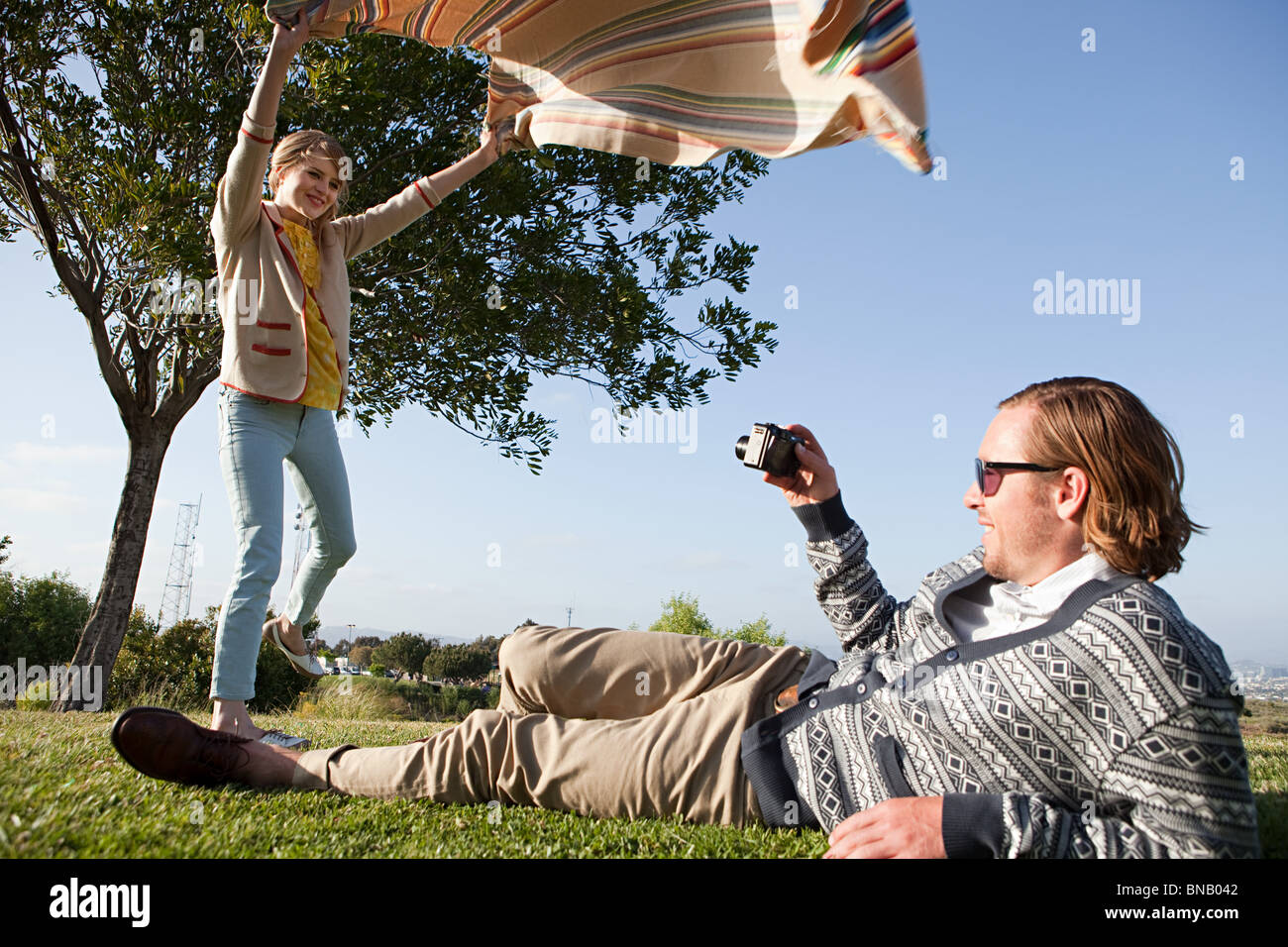 Young man photographing girlfriend as she shakes out a blanket Stock ...
