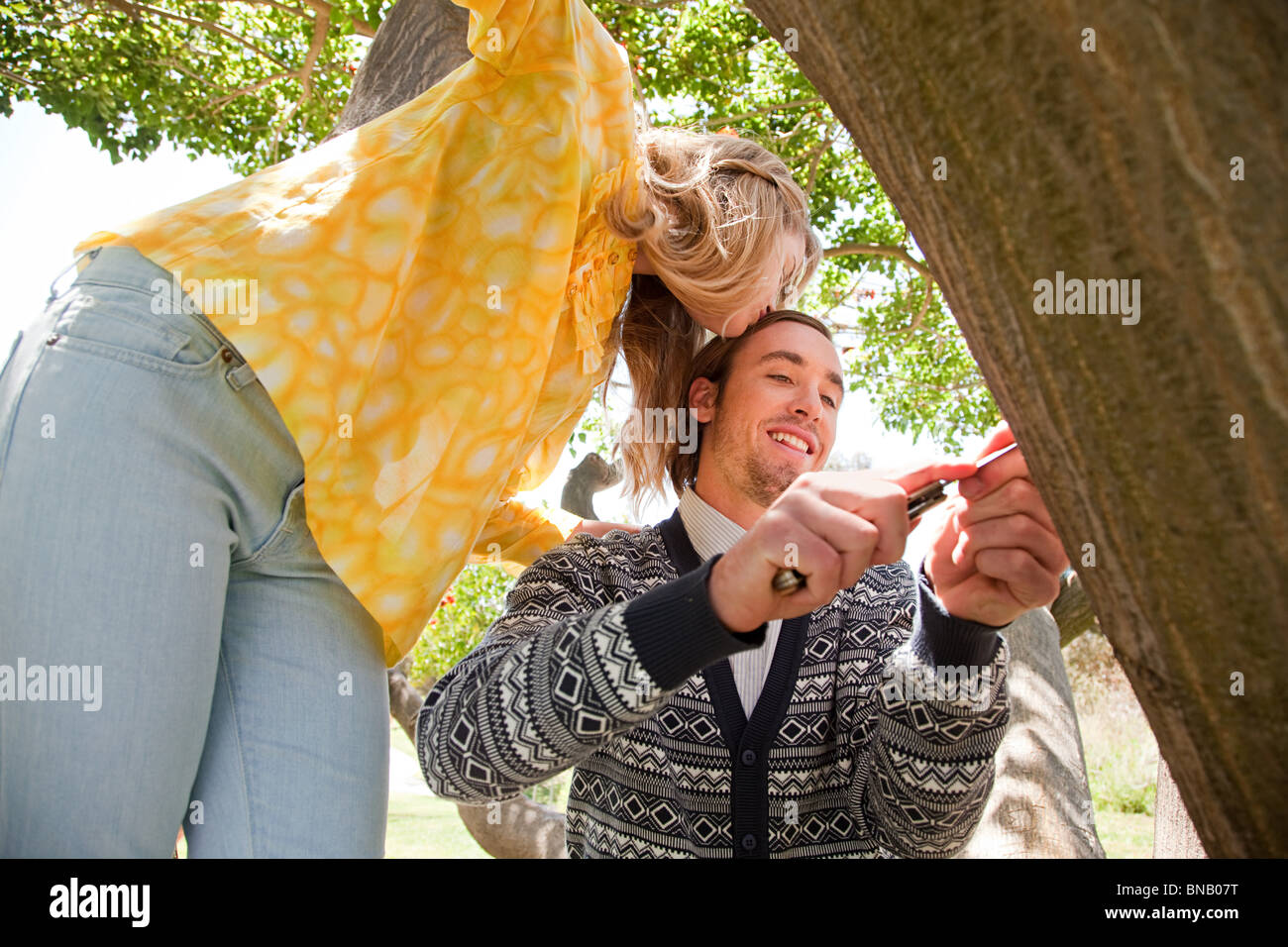 Young couple carving names on tree hi-res stock photography and images ...