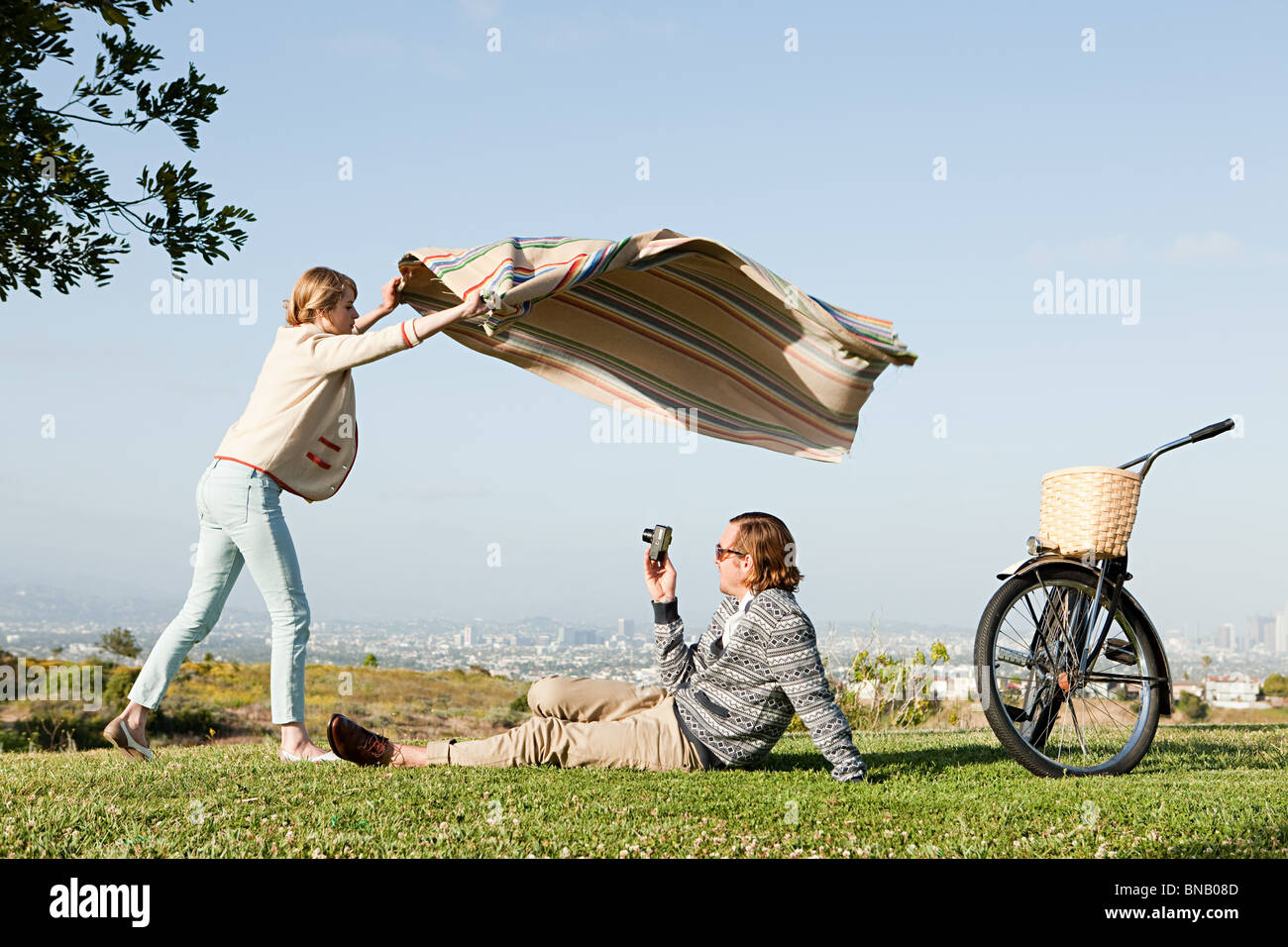 Young man photographing girlfriend as she shakes out a blanket Stock ...