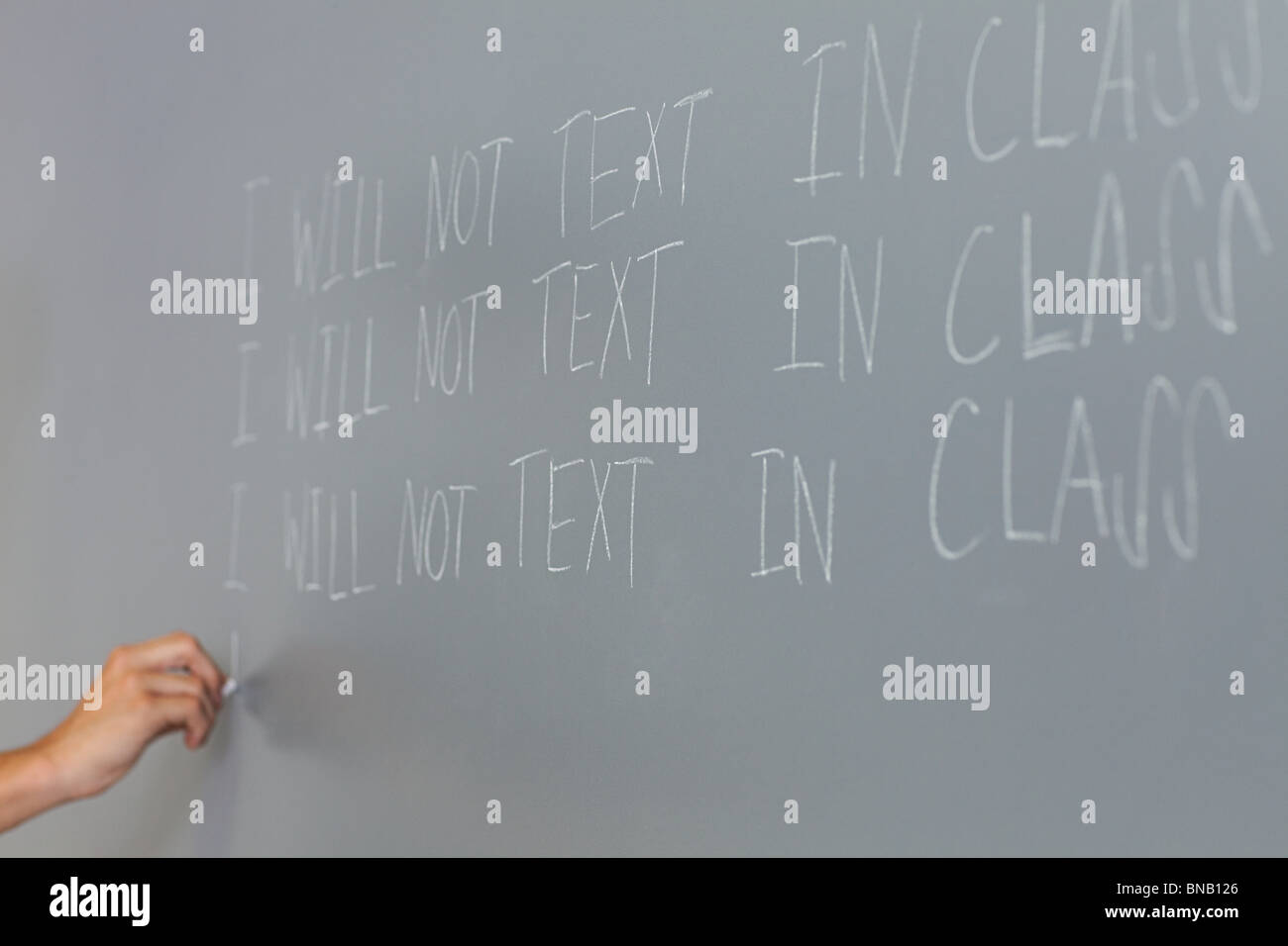 Male high school student writing lines on blackboard Stock Photo - Alamy