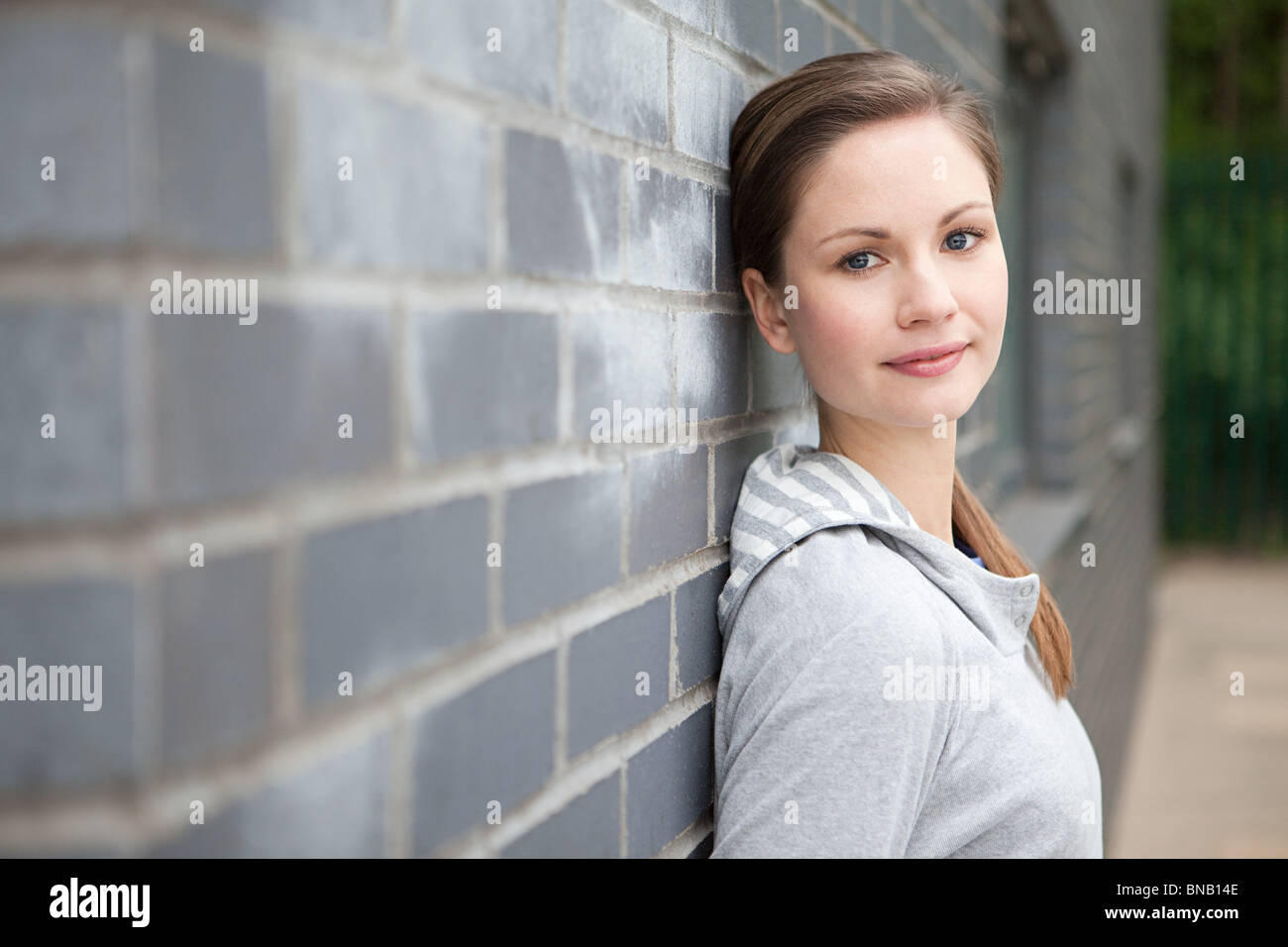 Young woman by wall Stock Photo - Alamy