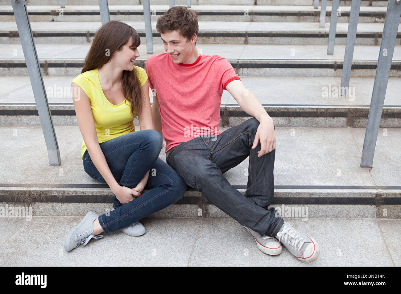 Young couple sitting on steps Stock Photo - Alamy