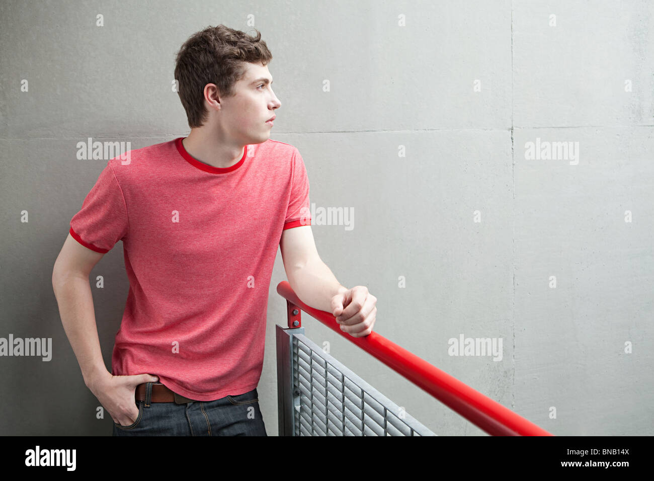 Young man by railing Stock Photo - Alamy