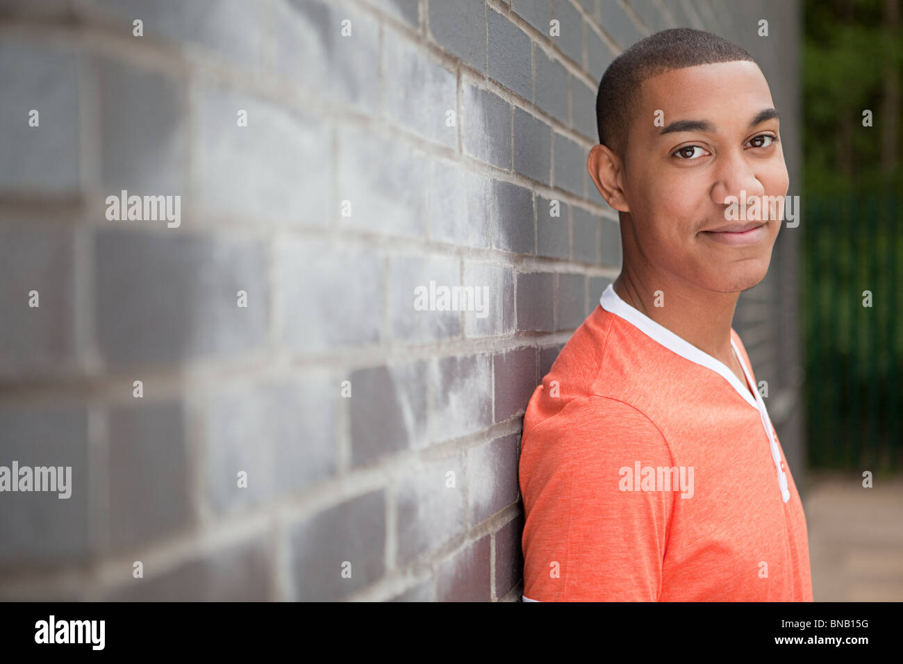 Young man by wall Stock Photo - Alamy
