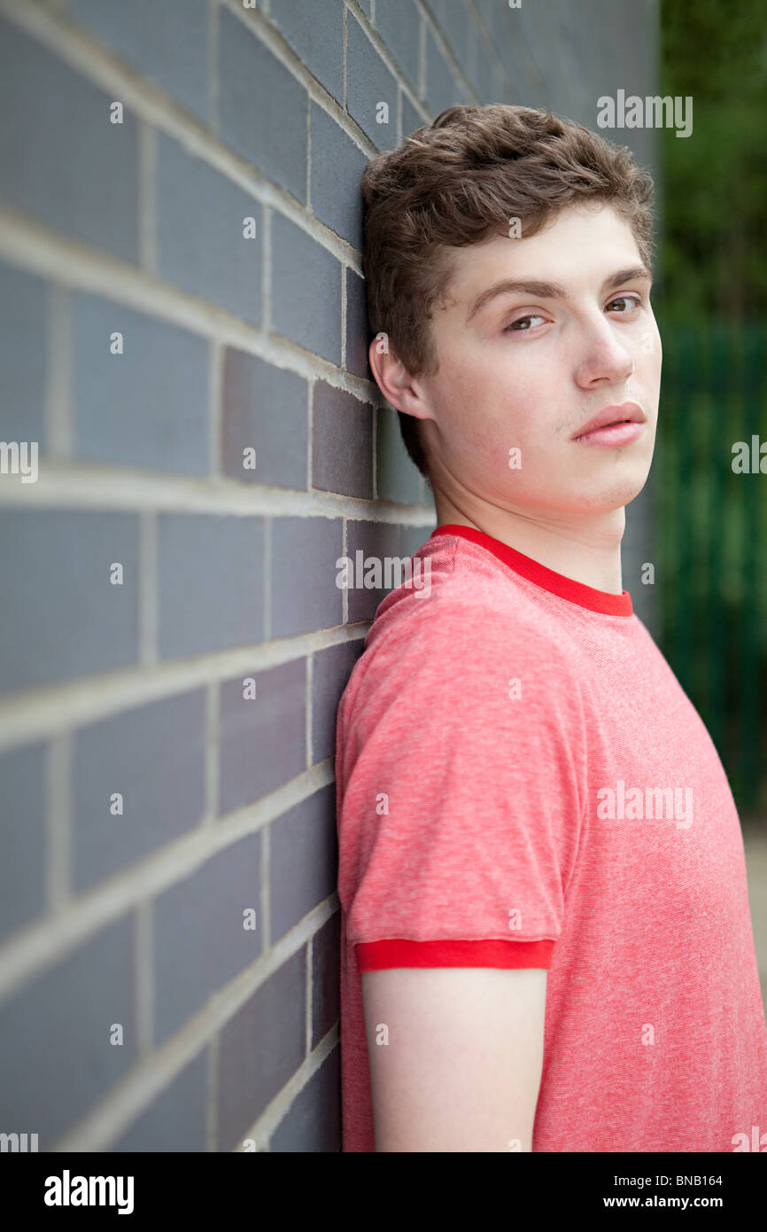 Young man by wall Stock Photo - Alamy