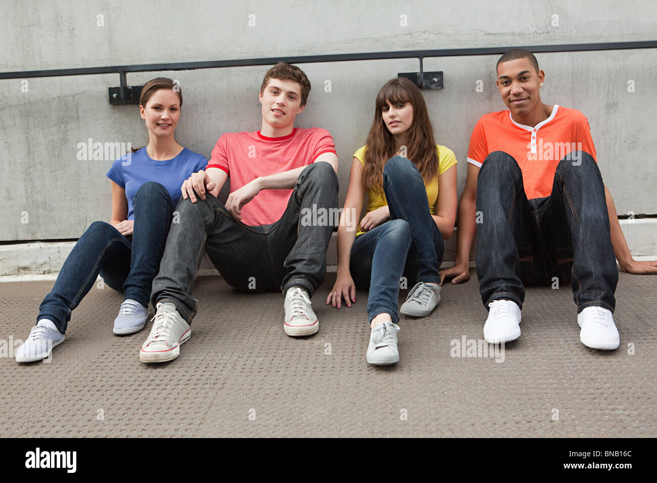 Young people sitting in row Stock Photo - Alamy