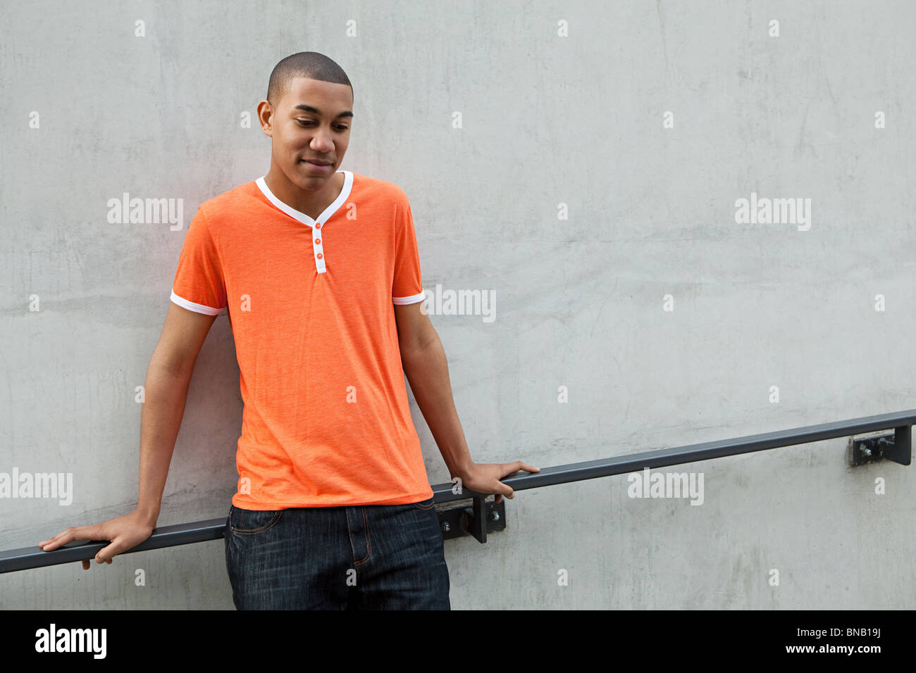Young man by railing Stock Photo - Alamy