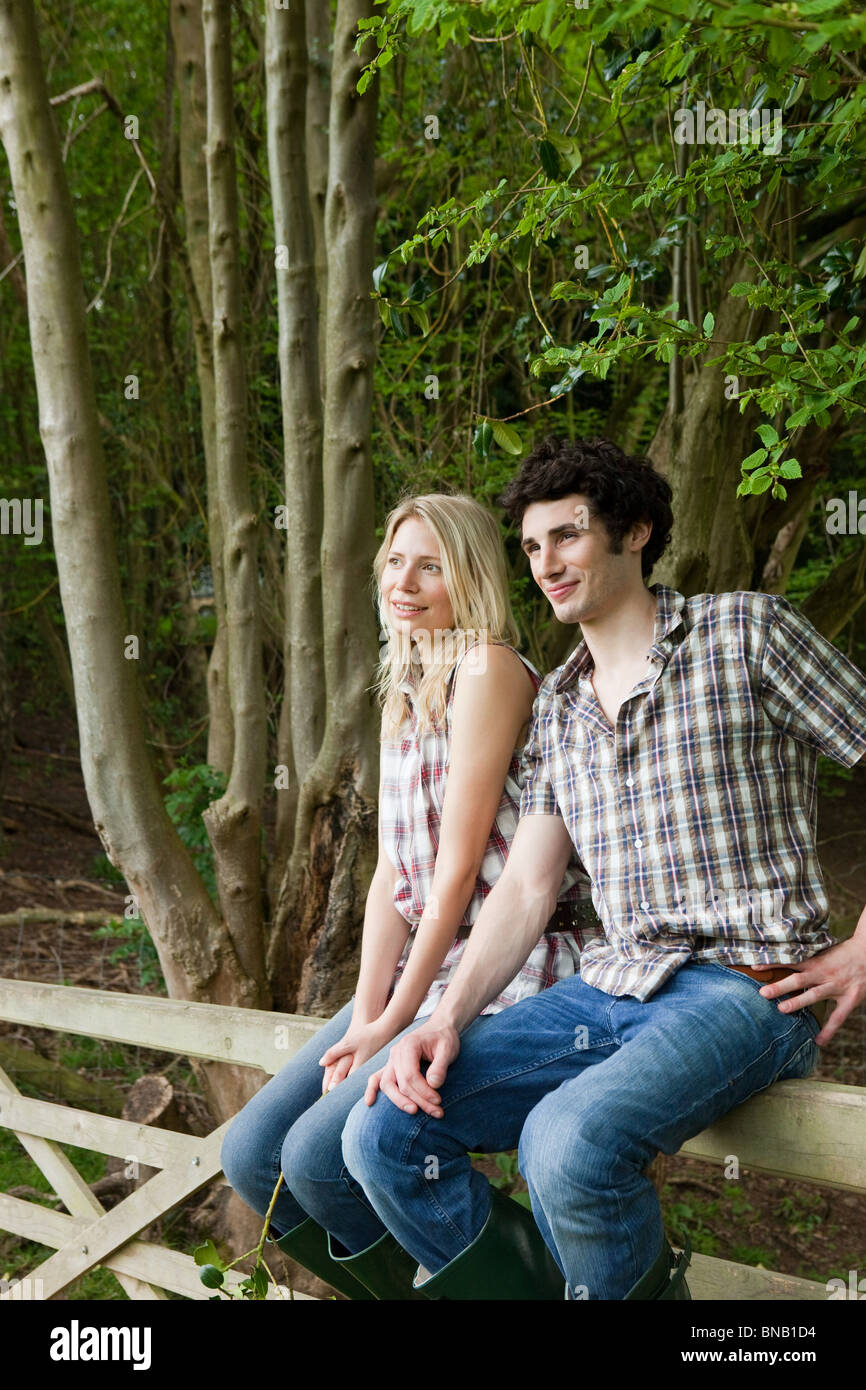 Young couple sitting on gate Stock Photo - Alamy