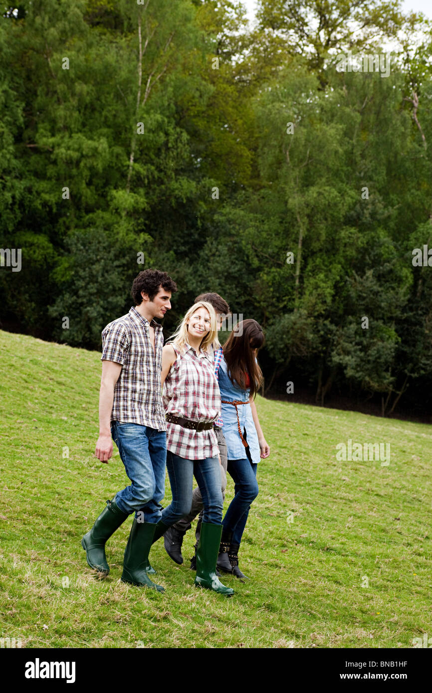 Young adult friends walking down hill Stock Photo - Alamy