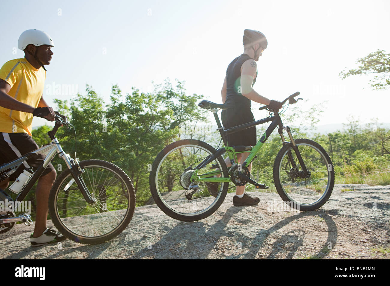 Two cyclists pushing bikes Stock Photo - Alamy
