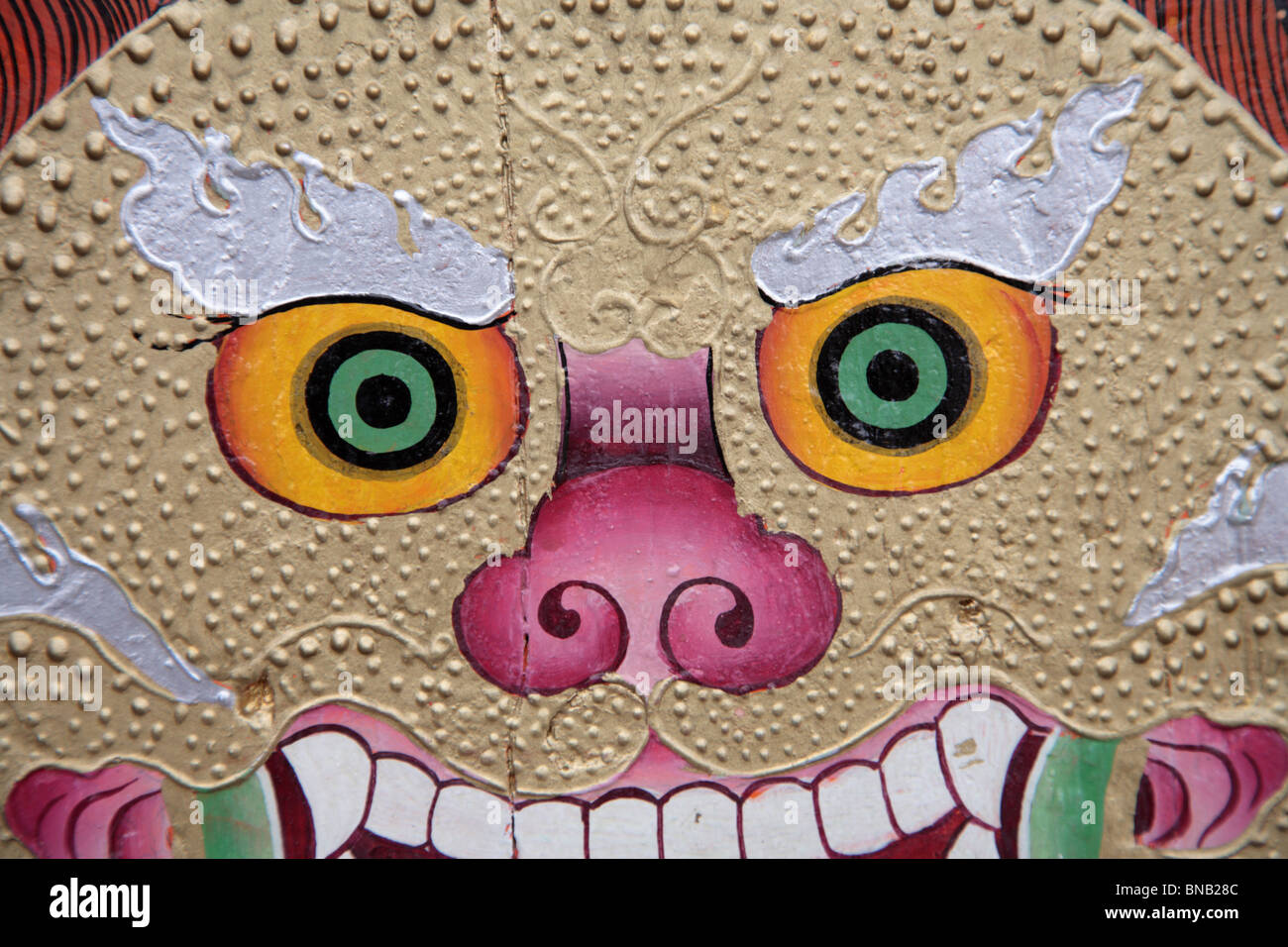 The face of a demon on a decorative mural in the Labrang monastery near ...