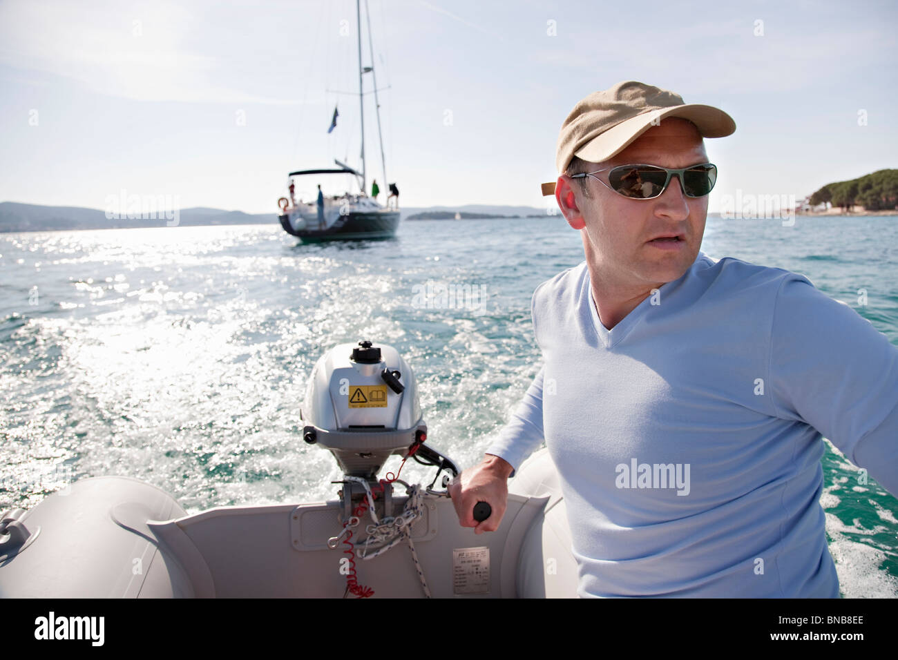 Man steering yacht dinghy Stock Photo - Alamy