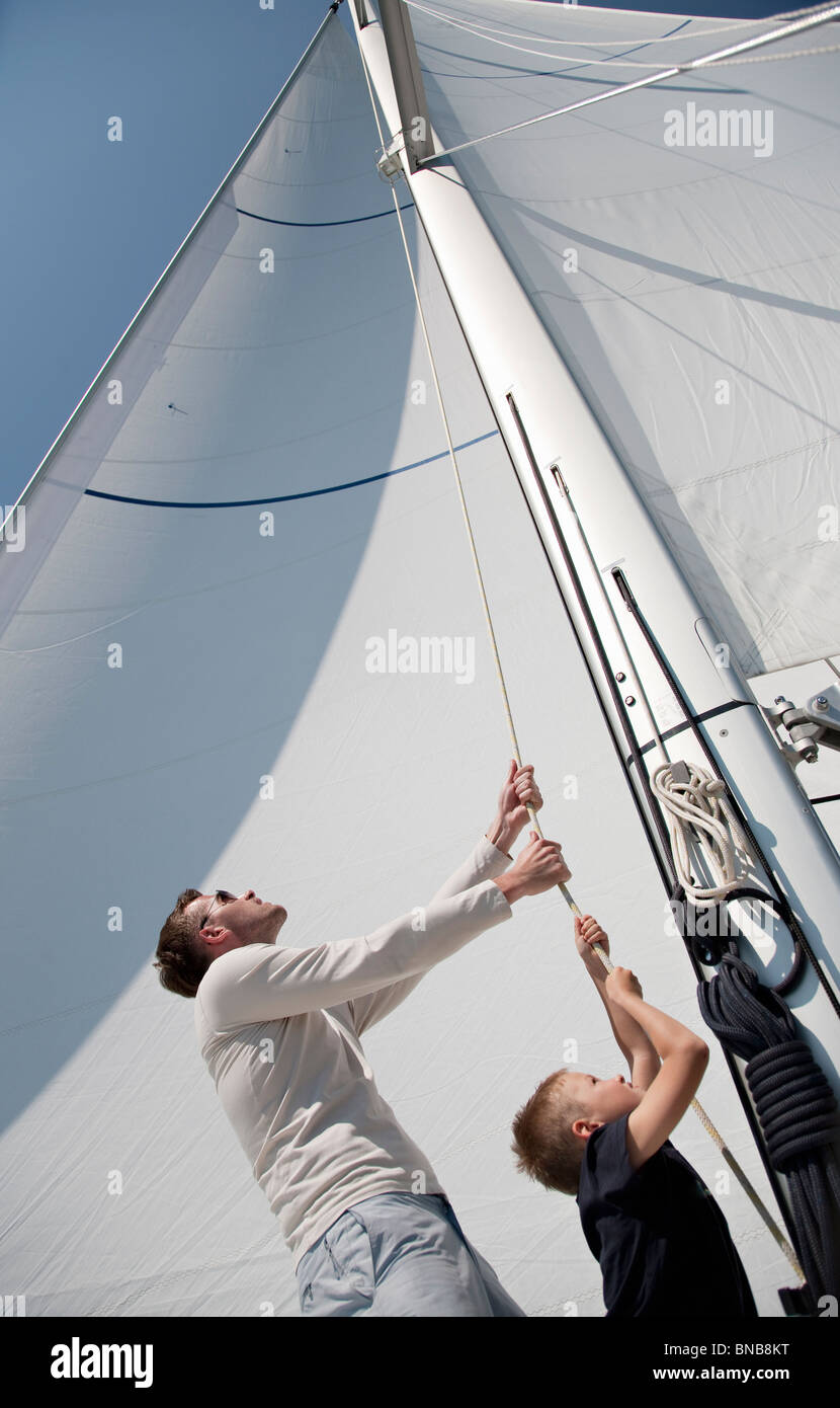 Father and son pulling rope on yacht Stock Photo - Alamy
