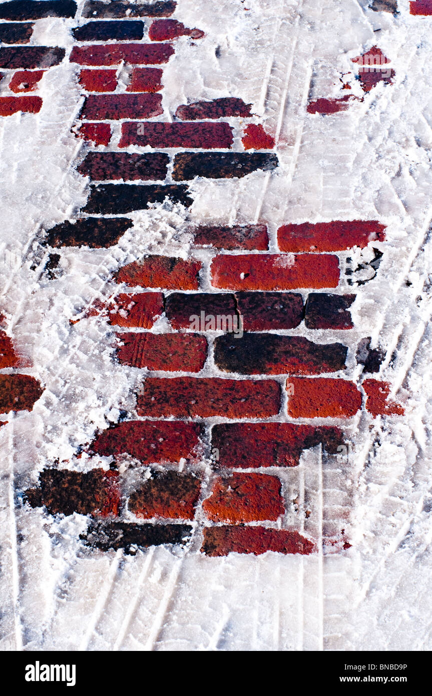 Tire tracks cover snowy areas of a section of red brick cobblestones in ...