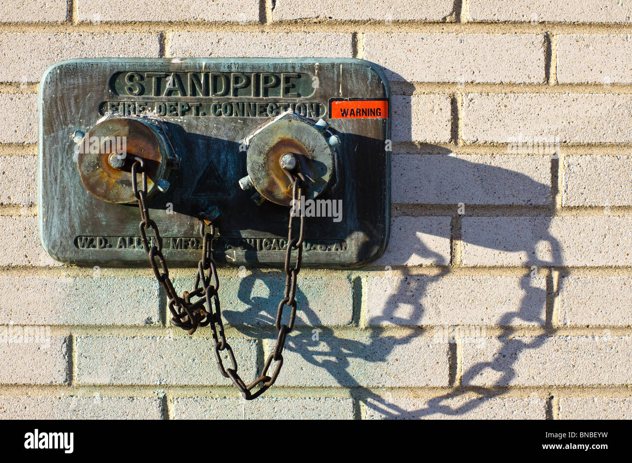 Fire department water standpipe connection against a white brick ...
