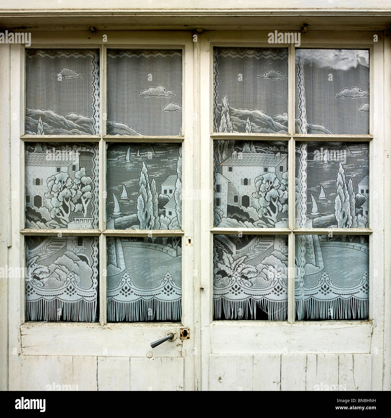 Intricate lace curtains adorn rustic wooden windows in a charming ...
