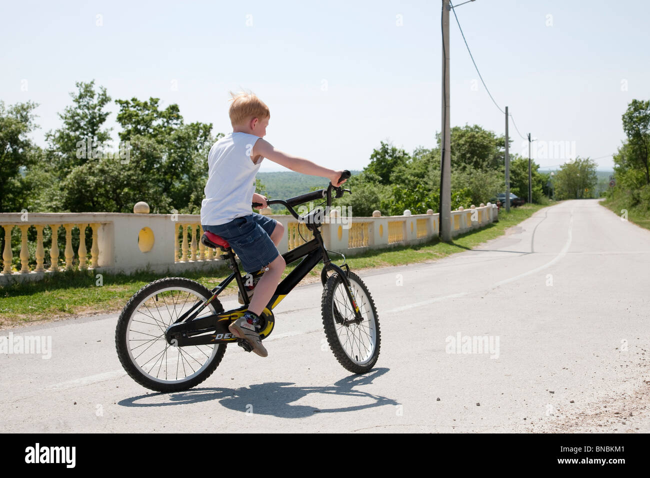 Boy on bicycle on country road Stock Photo - Alamy