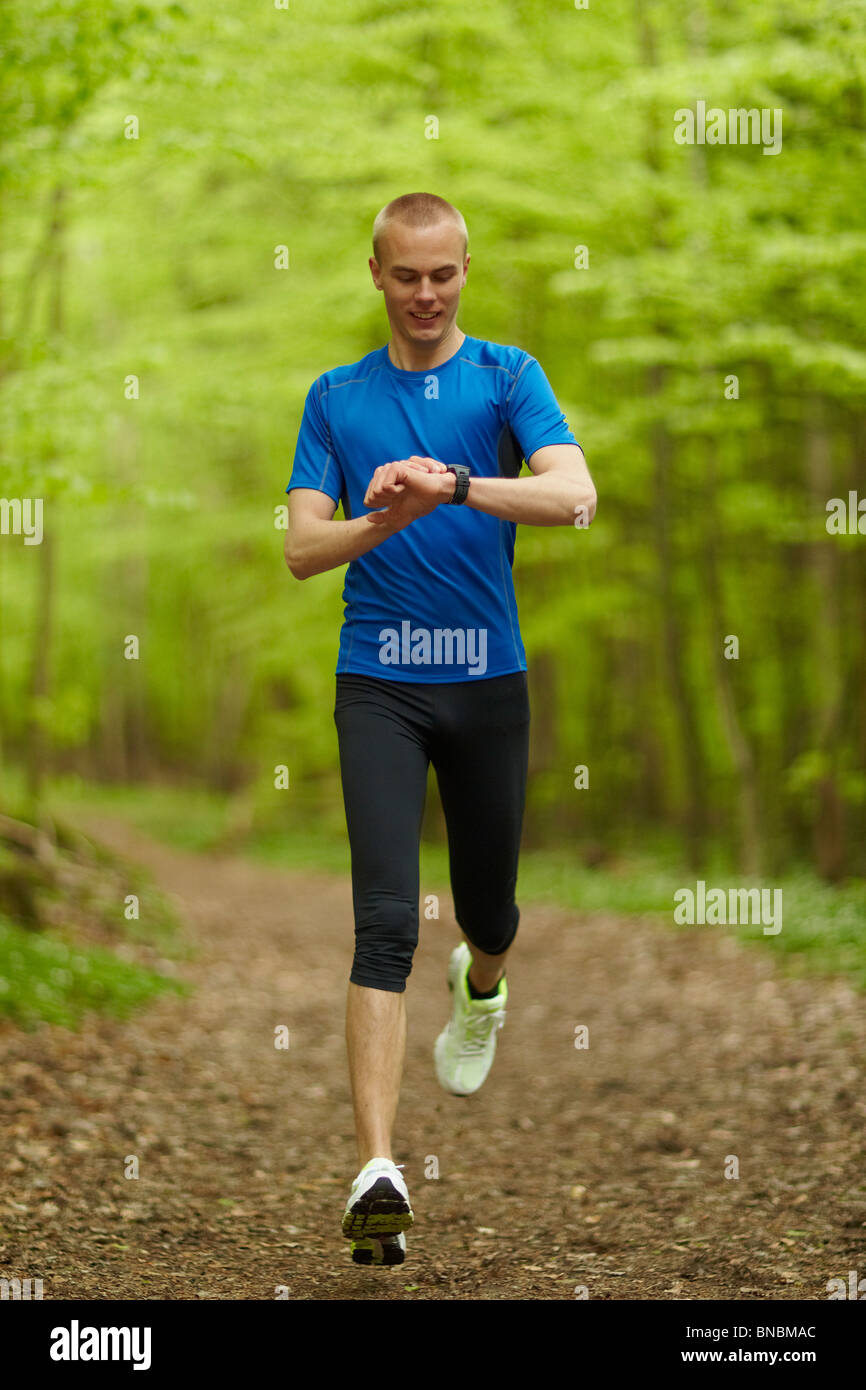 Man running, looking at sports watch Stock Photo - Alamy