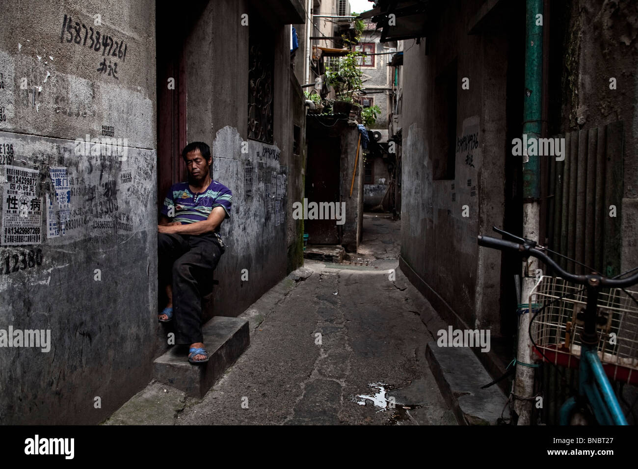 A cobbler waits for customers in an old neighbourhood in the Puxi area ...