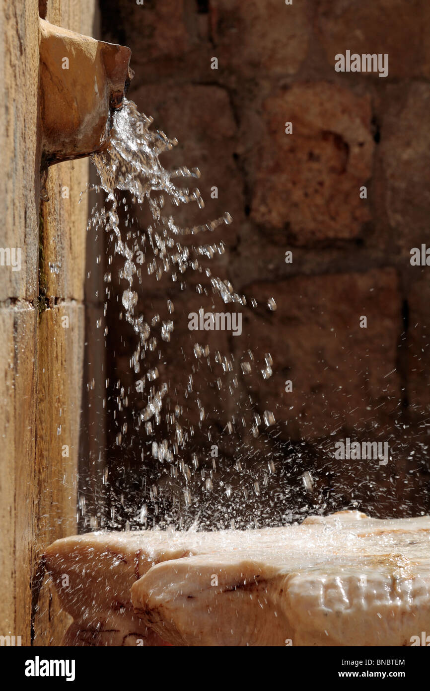 Water gushing from an outlet and splashing on an old marble column ...