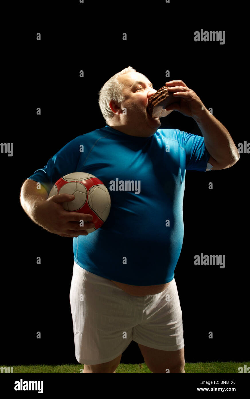 Large footballer holding ball and eating Stock Photo - Alamy