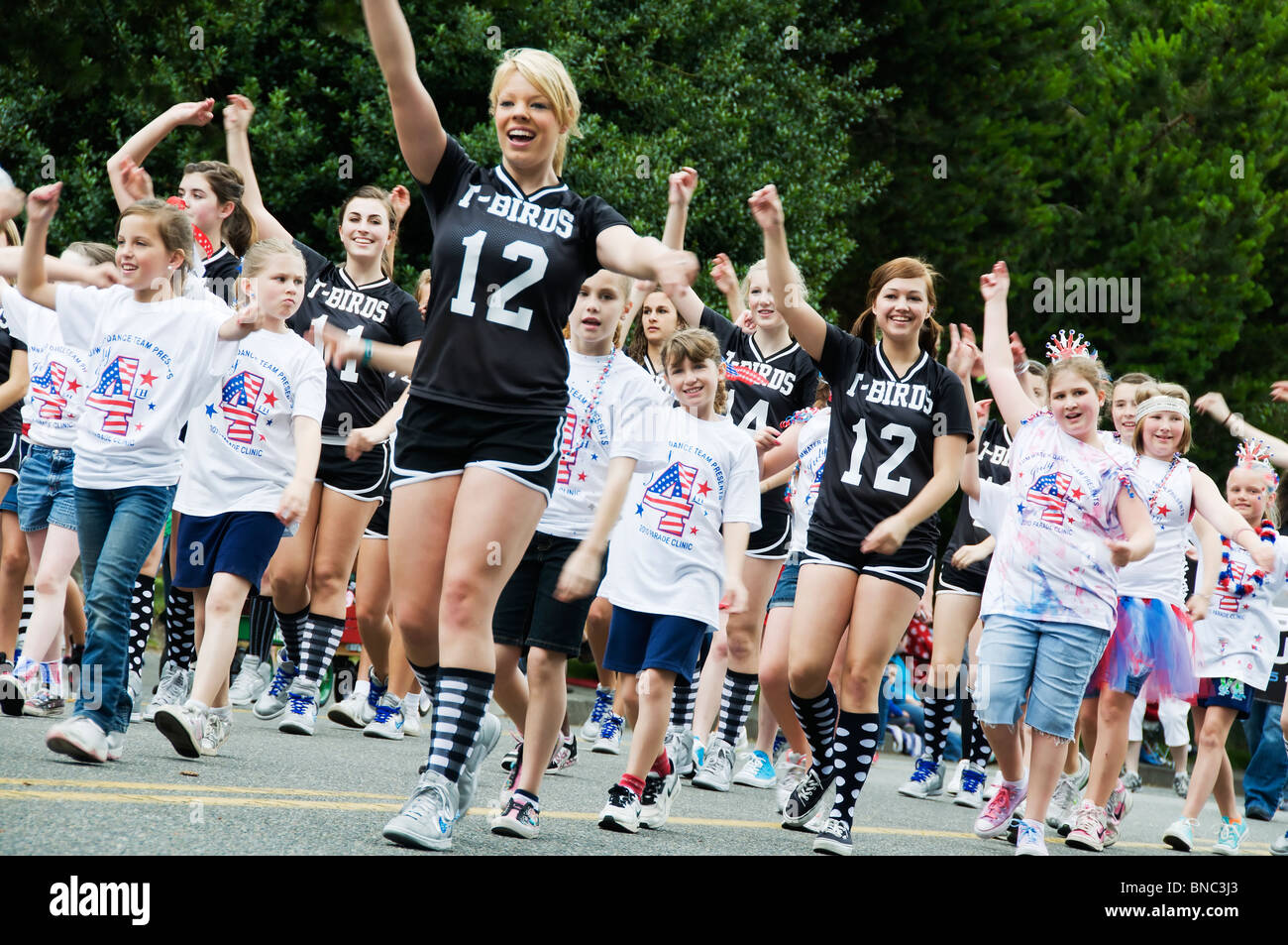 A group of cheerleaders and dance club members march down the street ...