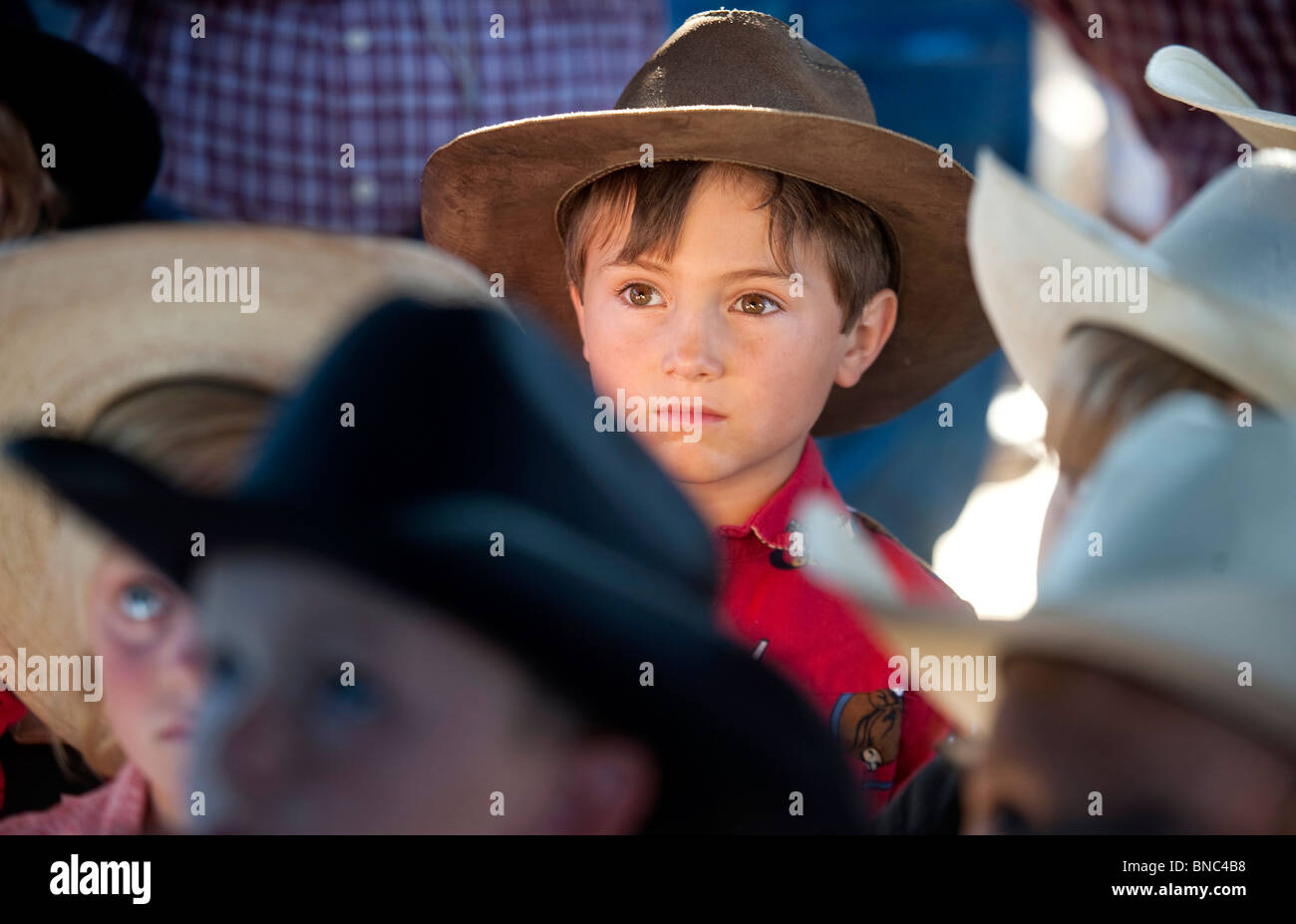 A six-year-old boy stands among other children at the rodeo Stock Photo ...