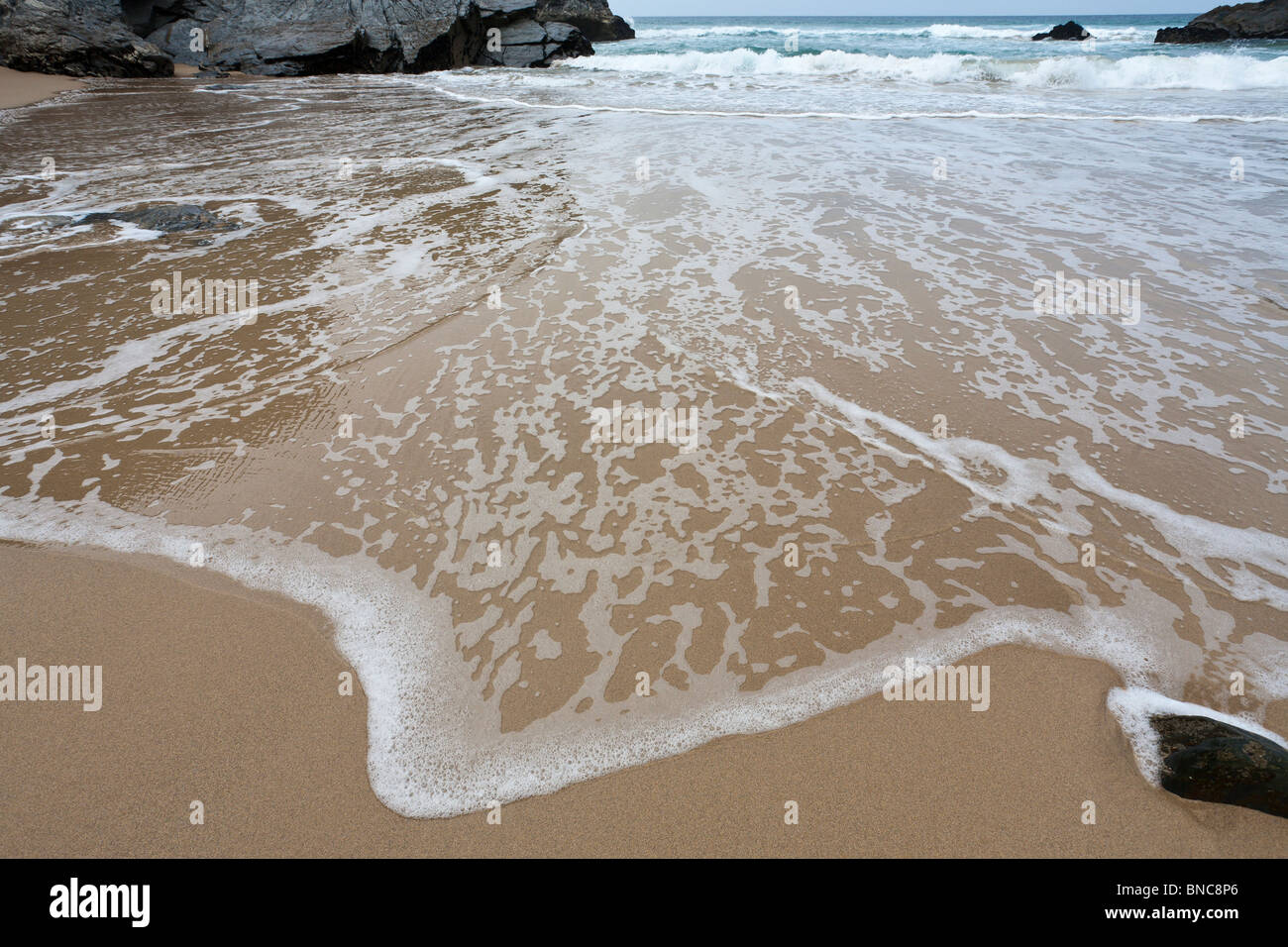 Waveforms at Bedruthan Beach. A wave flows smoothly over the flat sands ...