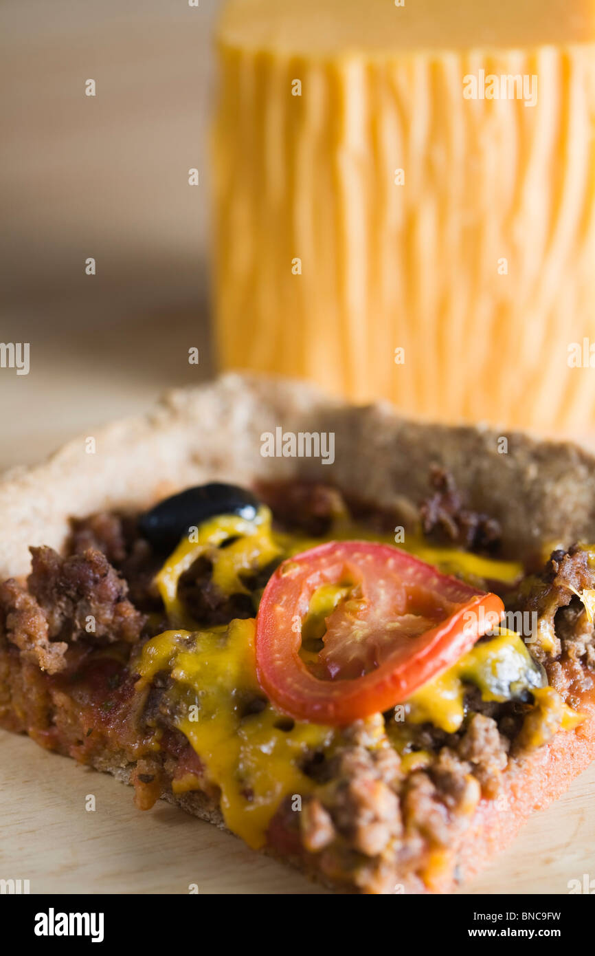 Cheeseburger pizza with wheat crust. Block of cheddar cheese in the ...