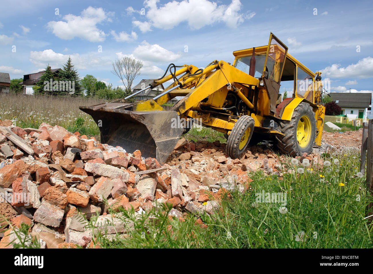 Yellow backhoe loader working with brick debris Stock Photo - Alamy