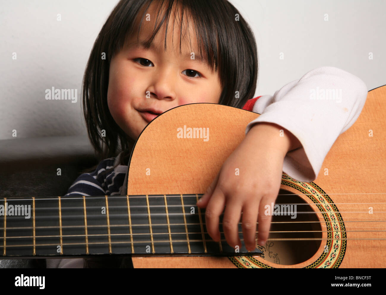 Chinese girl (age of 5) playing with a guitar Stock Photo - Alamy