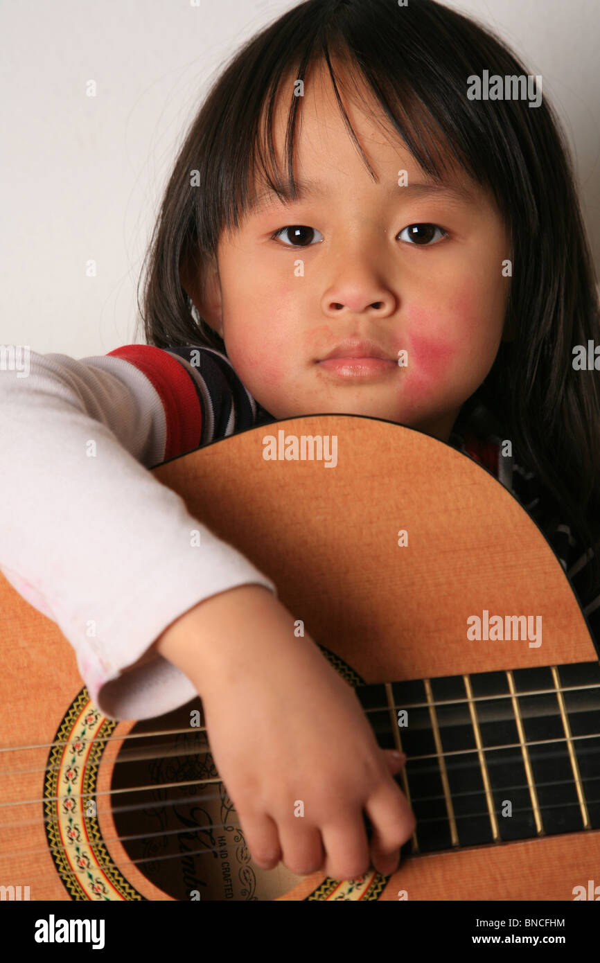 Chinese girl (age of 5) playing with a guitar Stock Photo - Alamy