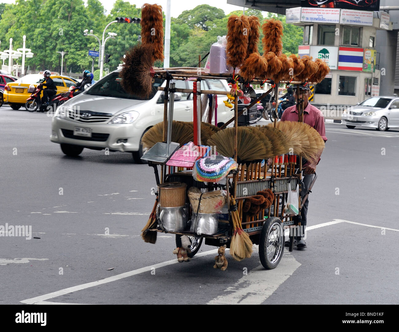 Street hawker pushing his wares across the junction at Silom in Bangkok ...