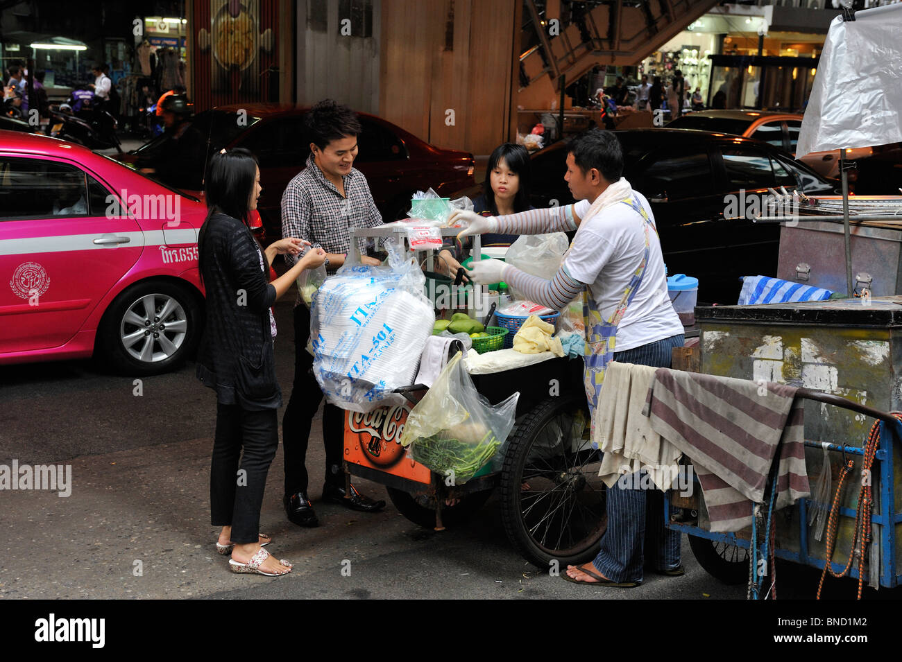 People buying food from a hawker stall on Silom Road, by the crowded ...
