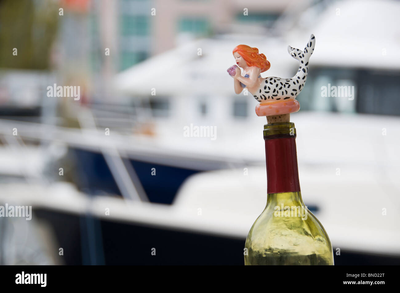 Mermaid cork tops a bottle of wine on-board a boat with other blurred ...
