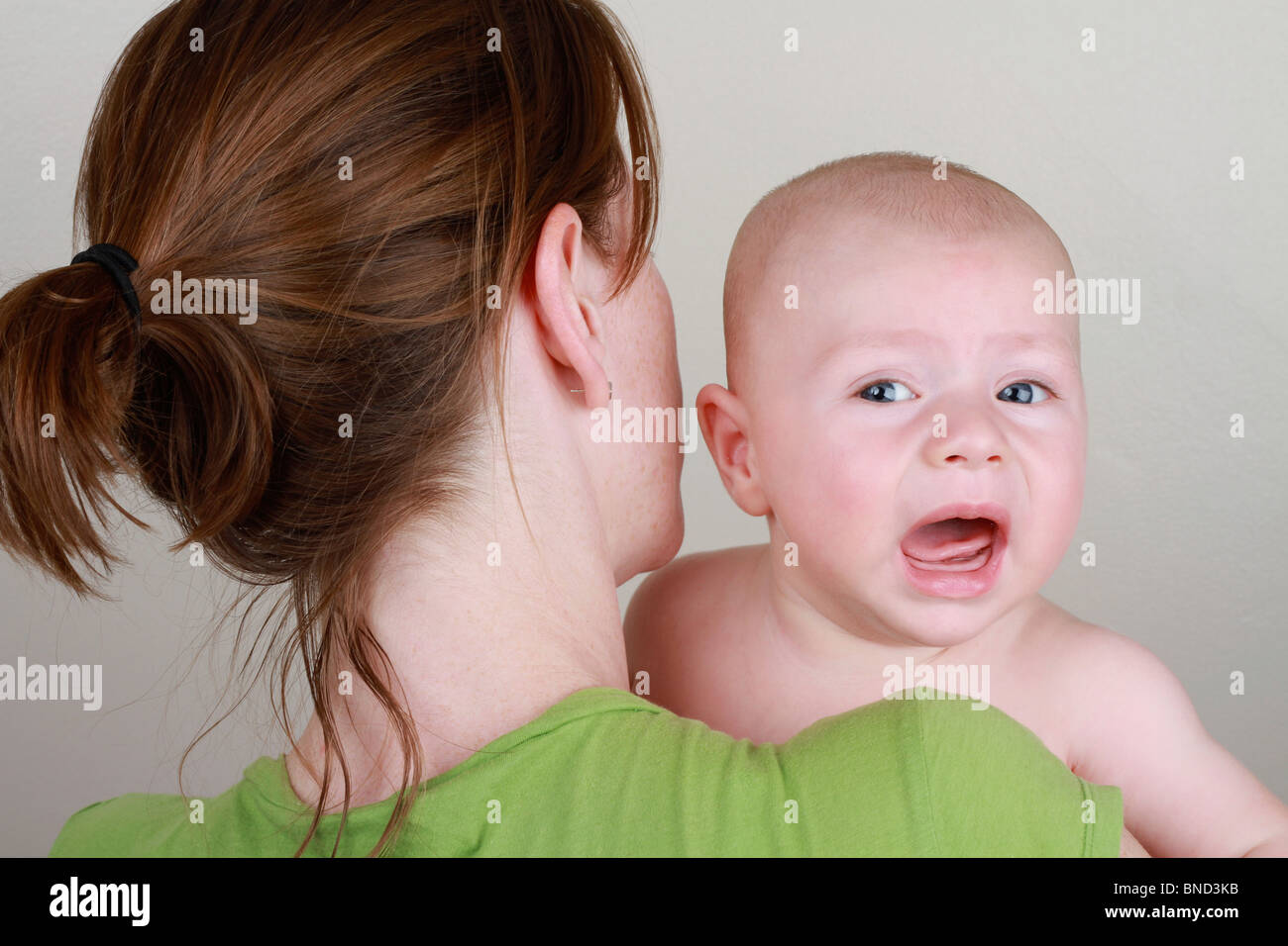 Crying and distressed baby boy being held and comforted by his mother ...