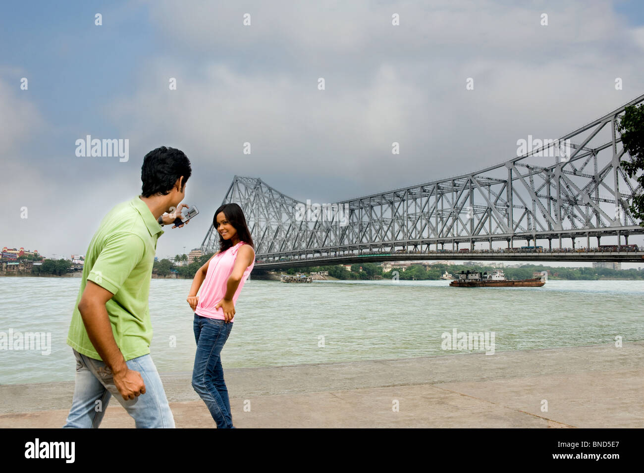 Man taking a picture of a woman with a bridge in the background, Howrah ...