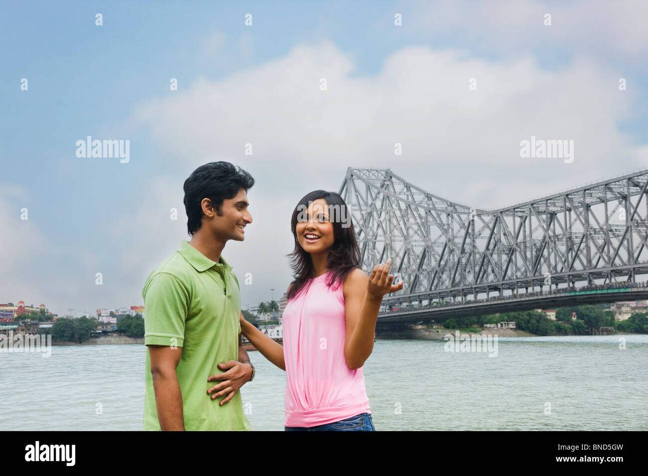 Couple smiling with a bridge in the background, Howrah Bridge, Hooghly ...